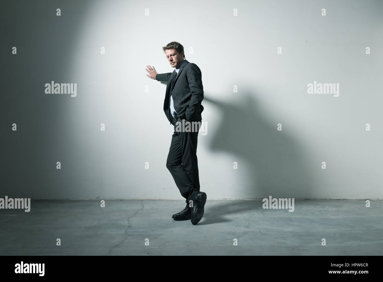 Tired pensive businessman leaning on a wall in an empty room with ...