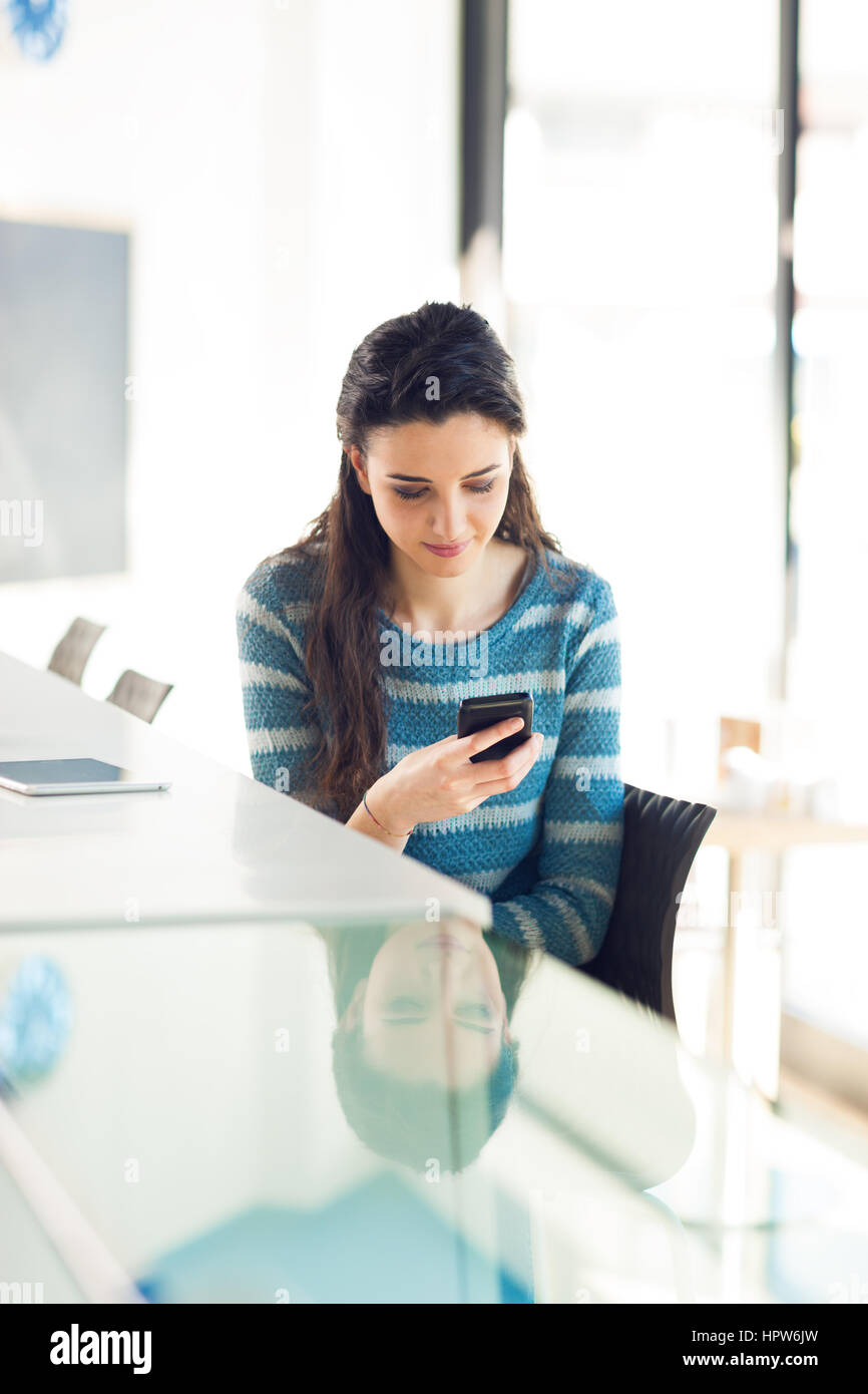 Young woman using a mobile phone next to a window Stock Photo - Alamy