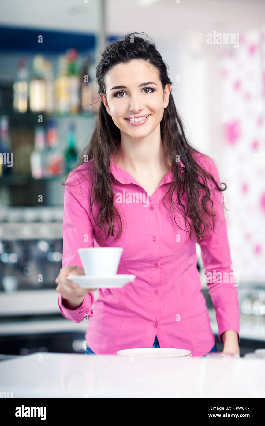 Cheerful smiling waitress in a coffee shop serving an hot espresso ...
