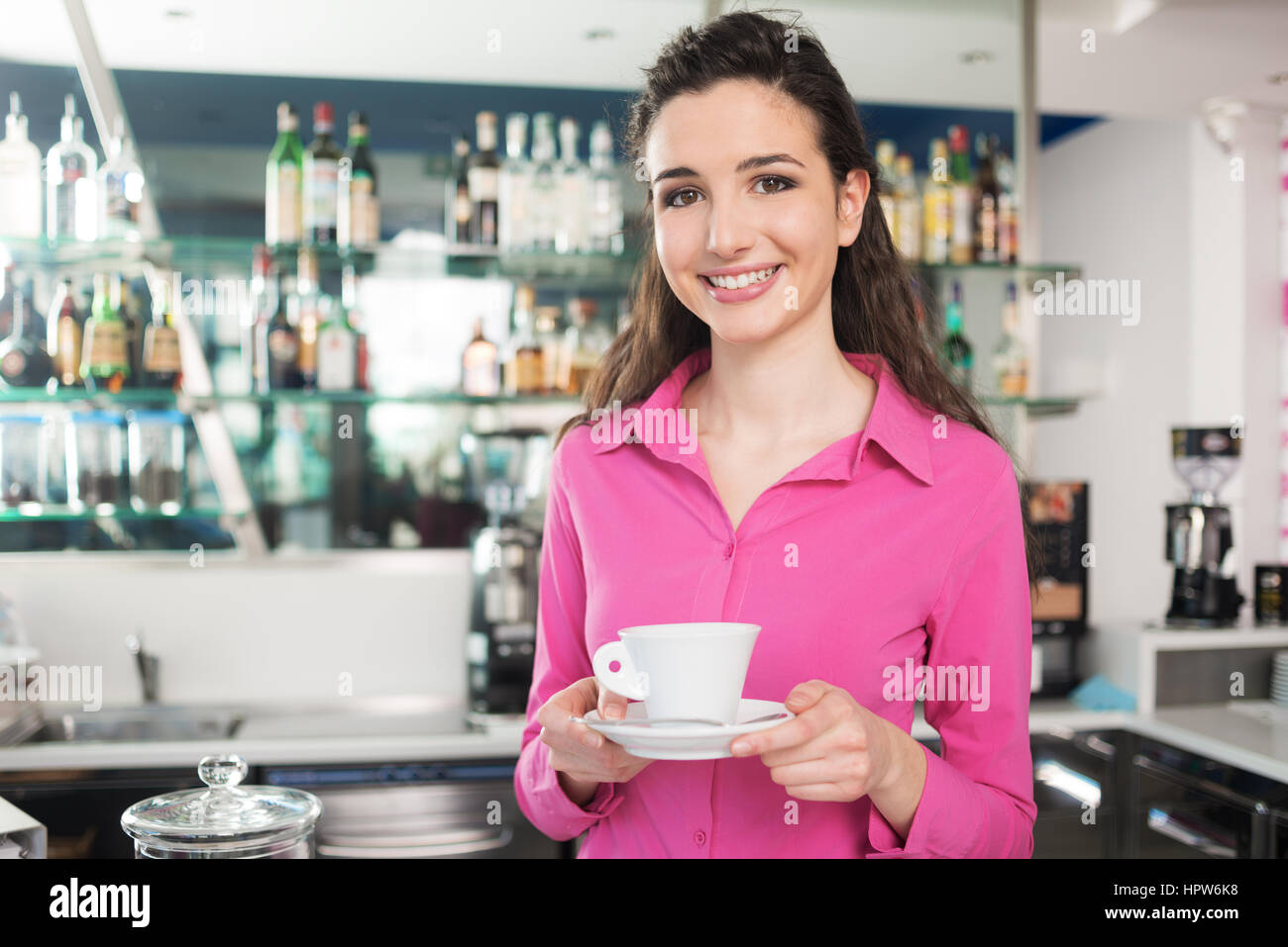 Cheerful smiling waitress in a coffee shop serving an hot espresso ...