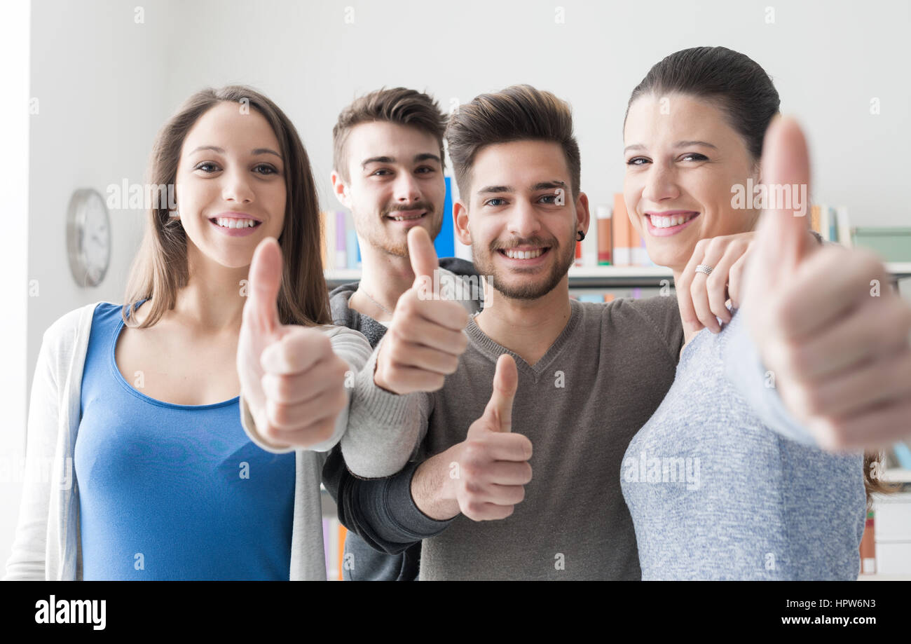 Cheerful group of students smiling at camera with thumbs up, success ...
