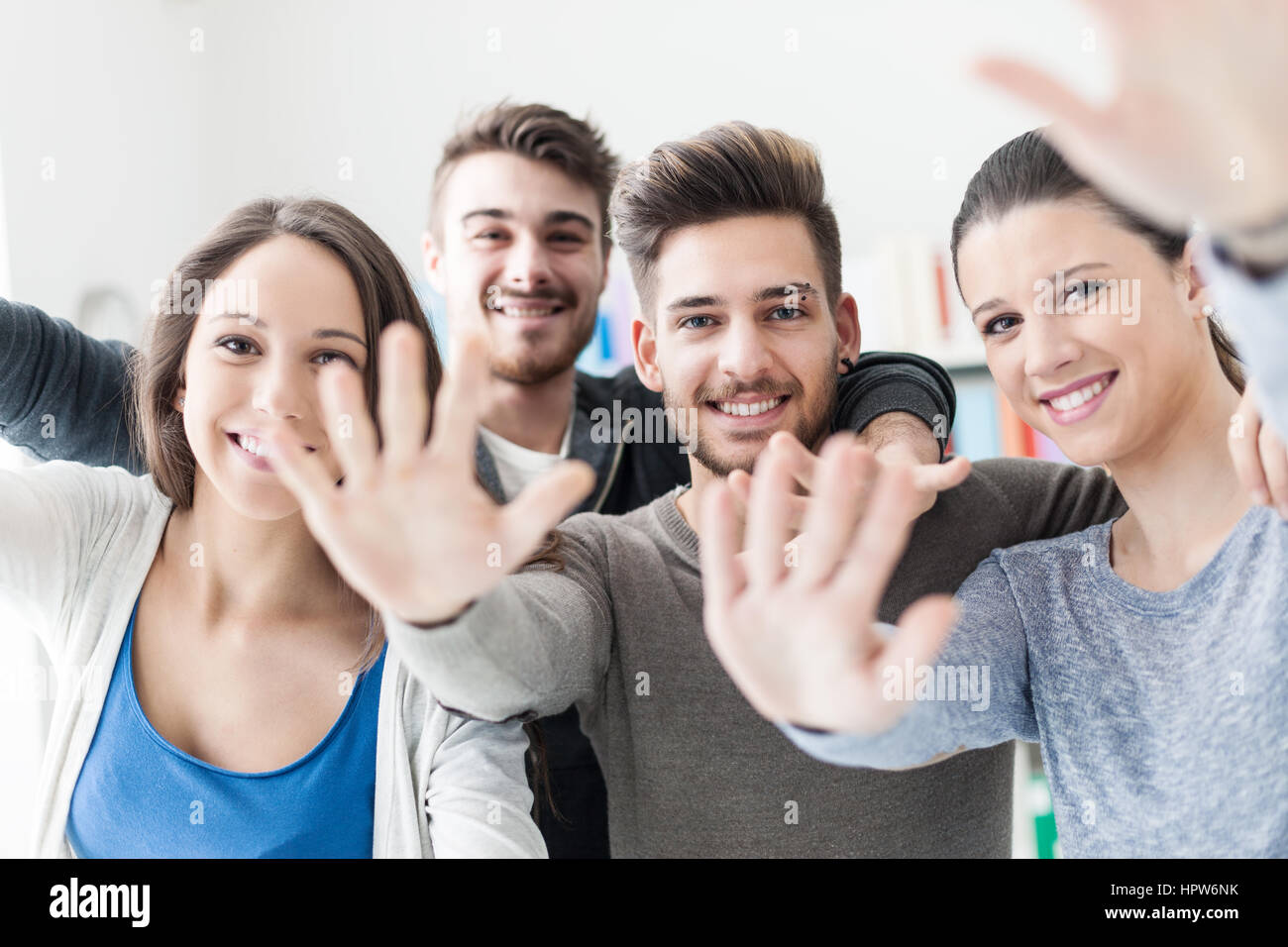 Cheerful group of friends posing and greeting with hands up, friendship ...