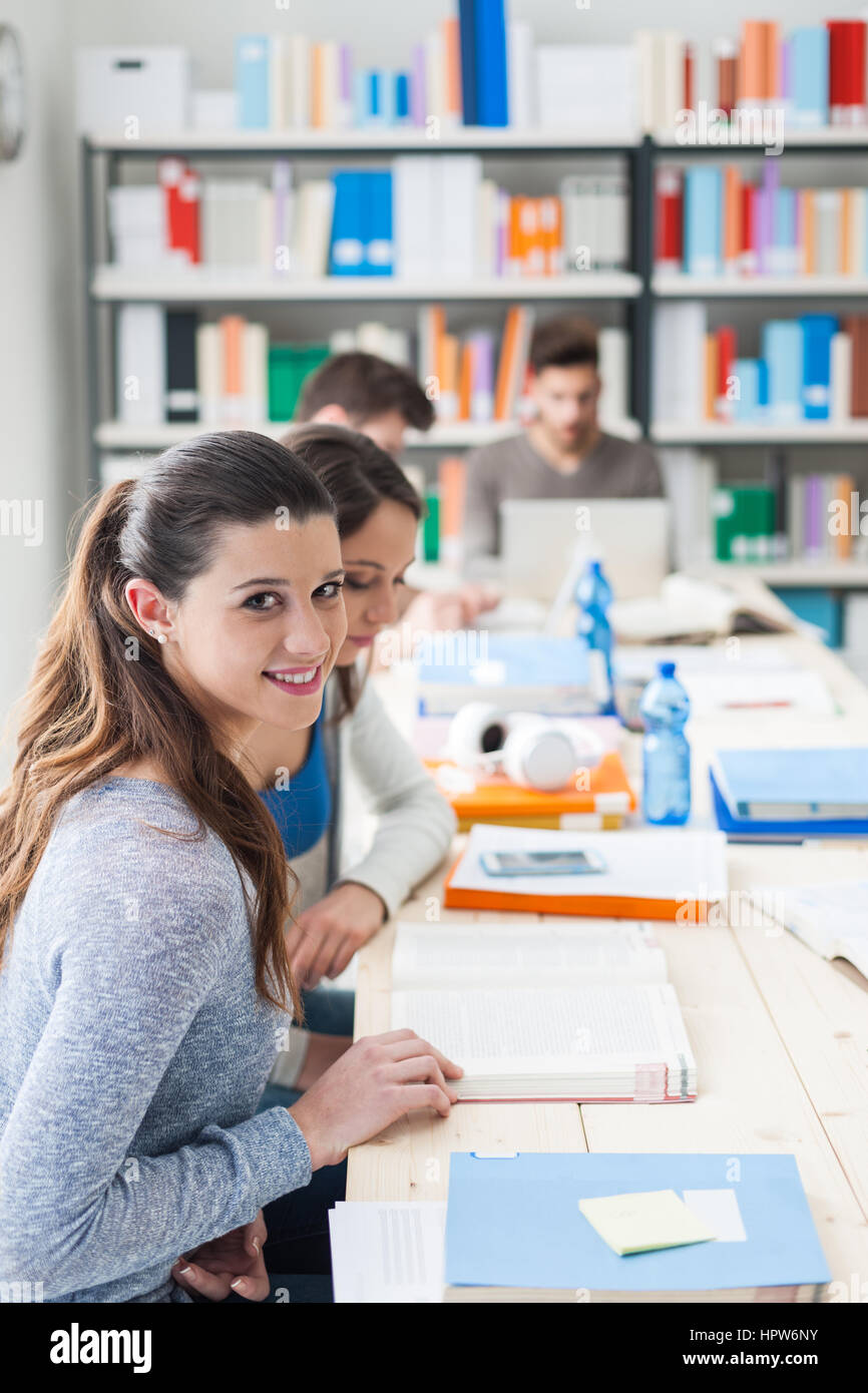 Girls studying together in the classroom, they are sitting at desk and ...
