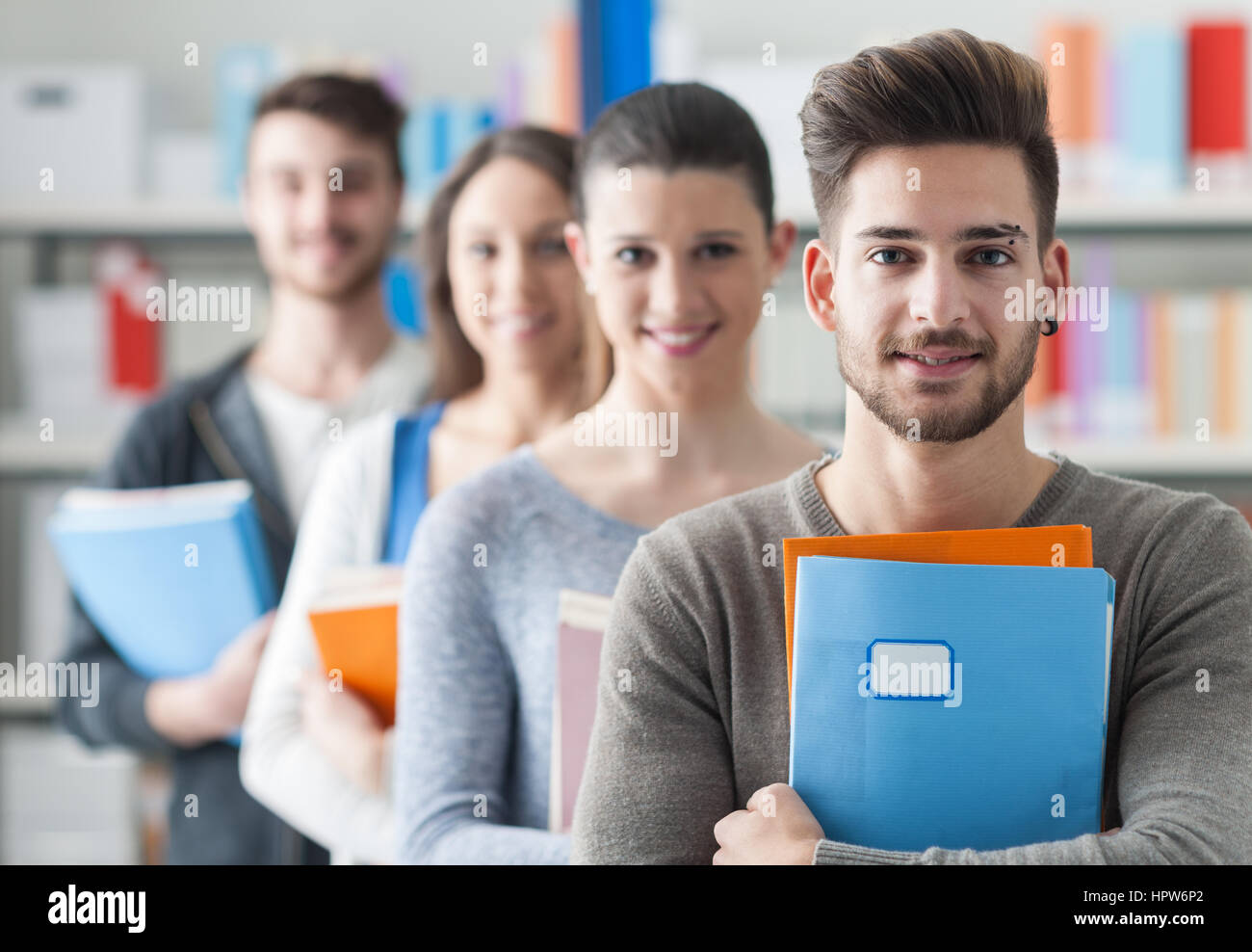 Group of college students in the library standing in line and looking ...