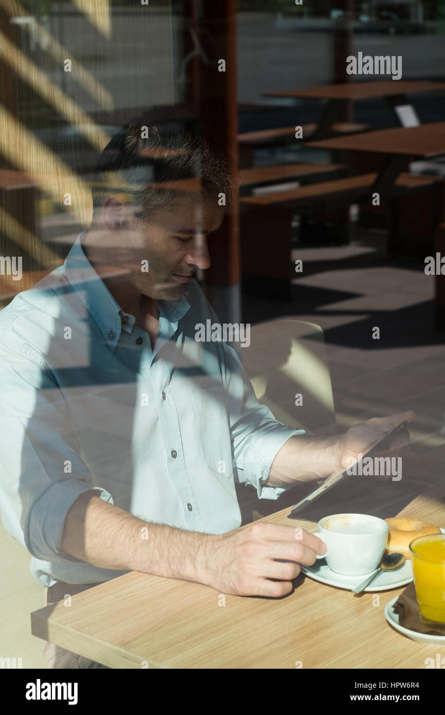 Man having breakfast at the cafe next to a window with reflections ...