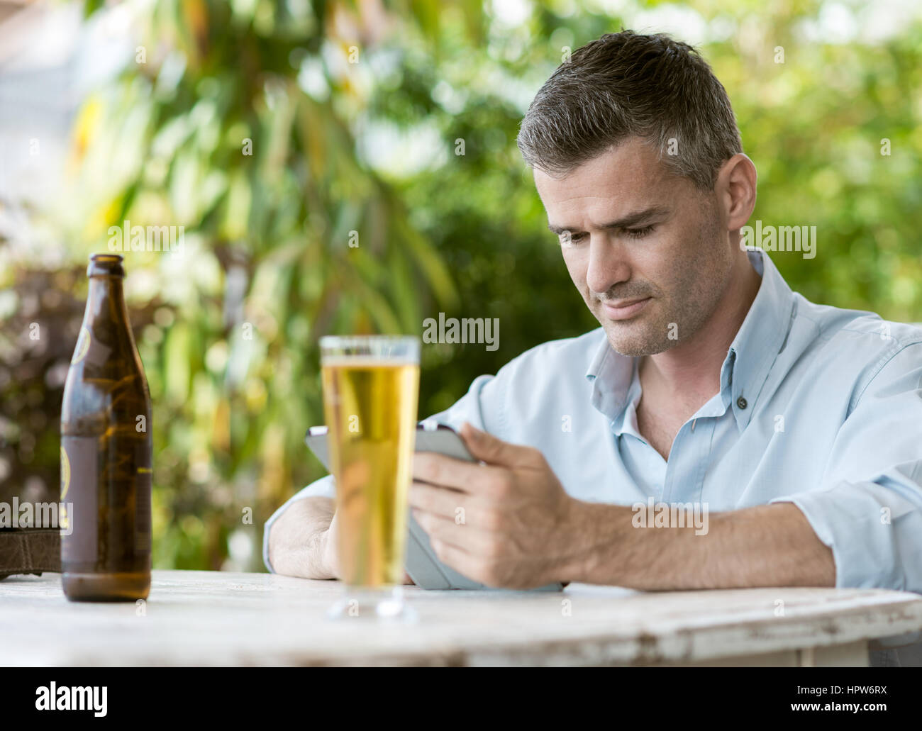 Smiling man relaxing at the bar, he is sitting at the table, having a ...