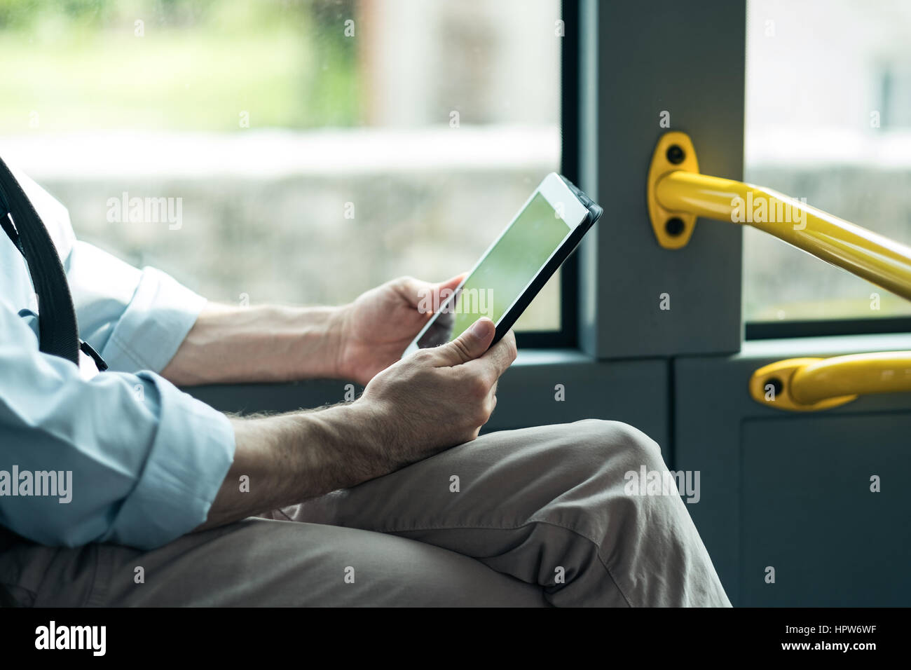 Man commuting to work by bus and working with a digital touch screen ...