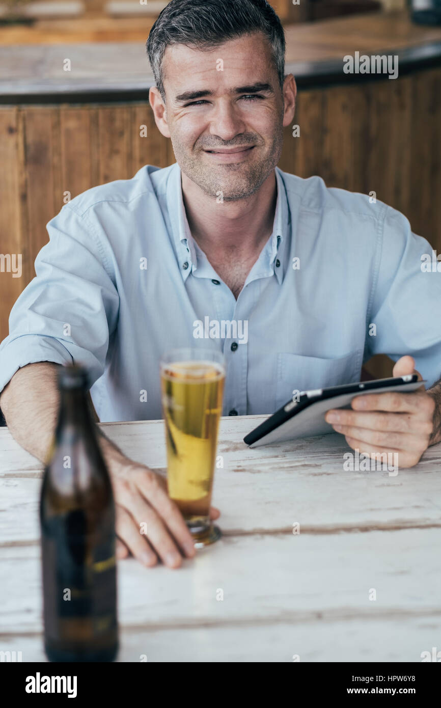 Man enjoying a refreshing break at the bar, he is drinking a beer and ...