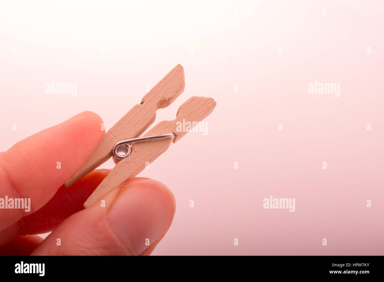 Hand holding a small wooden clothespin in hand Stock Photo - Alamy