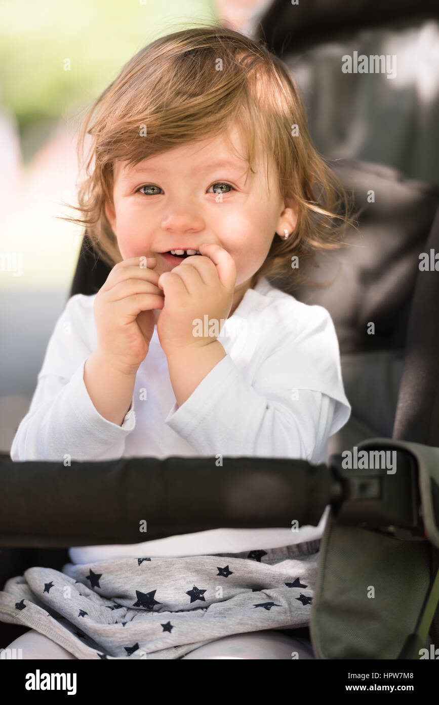 little and very beautiful baby girl sitting in the pram and waiting for ...