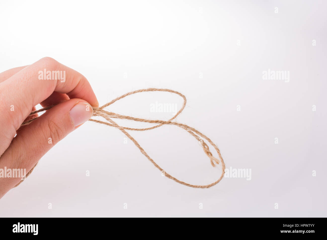 Hand holding linen thread on a white background Stock Photo - Alamy