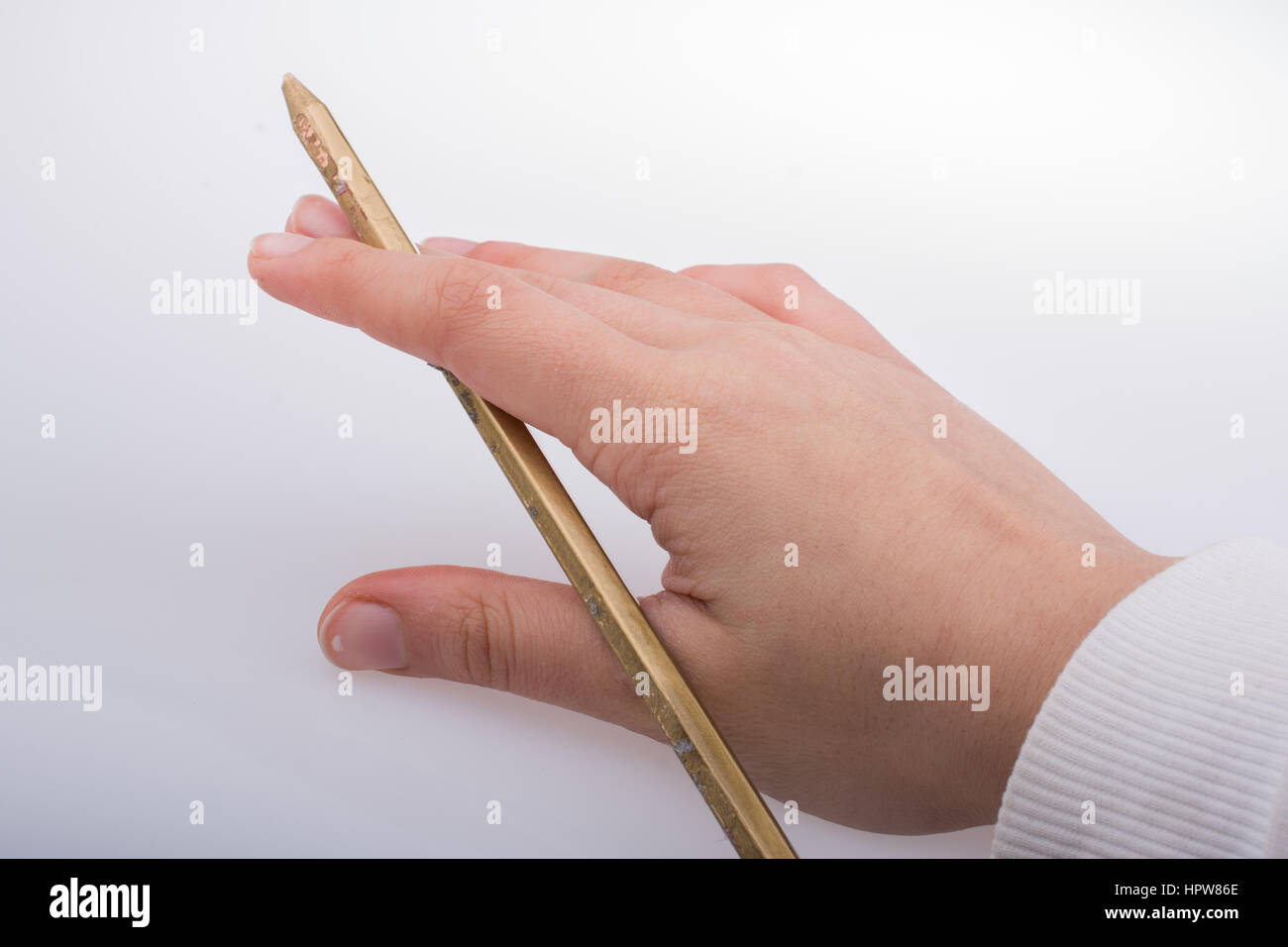 Hand holding a gold color pencil on a white background Stock Photo - Alamy