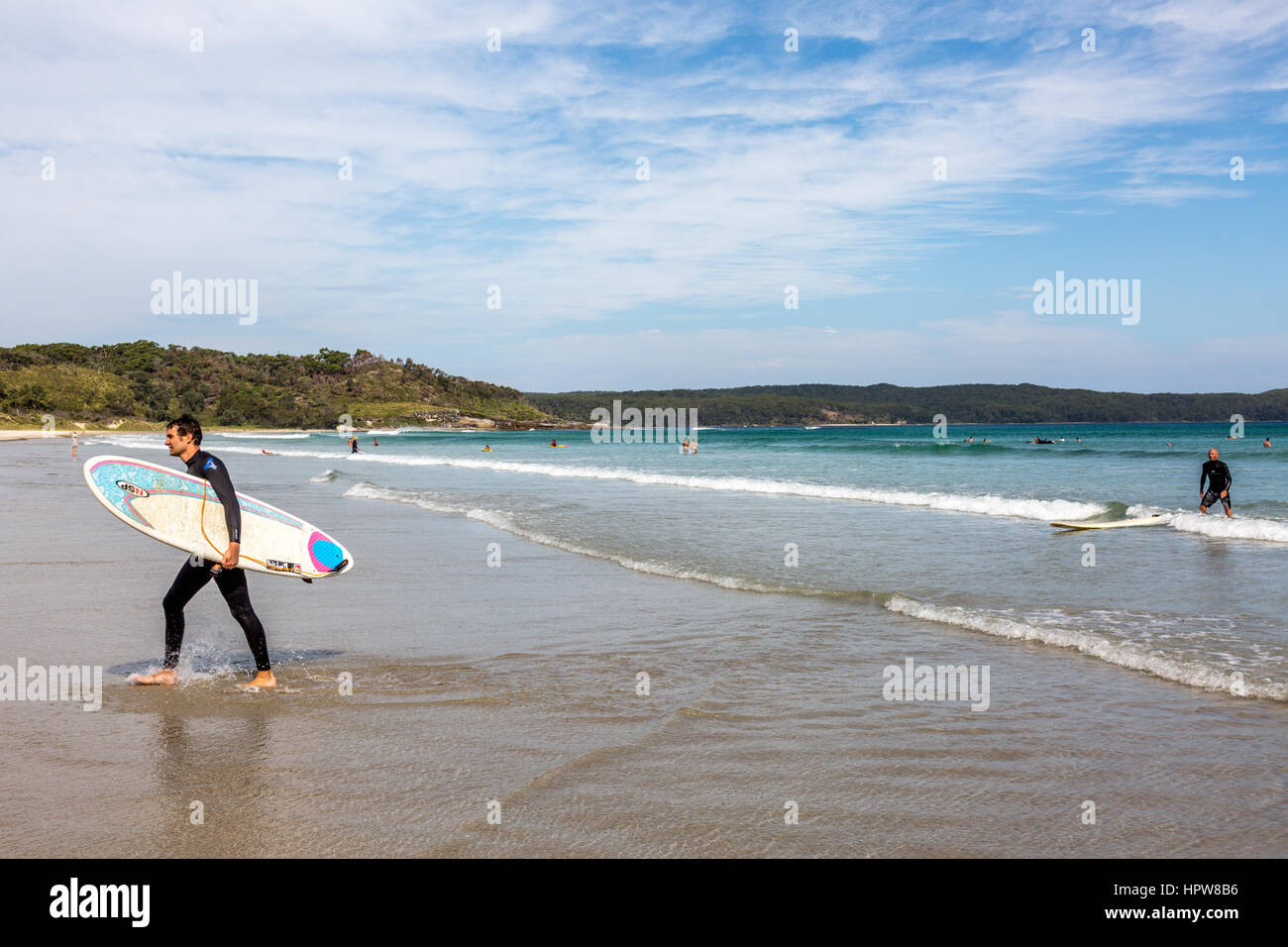 Man carrying a surfboard at popular Cave Beach in Booderee national ...