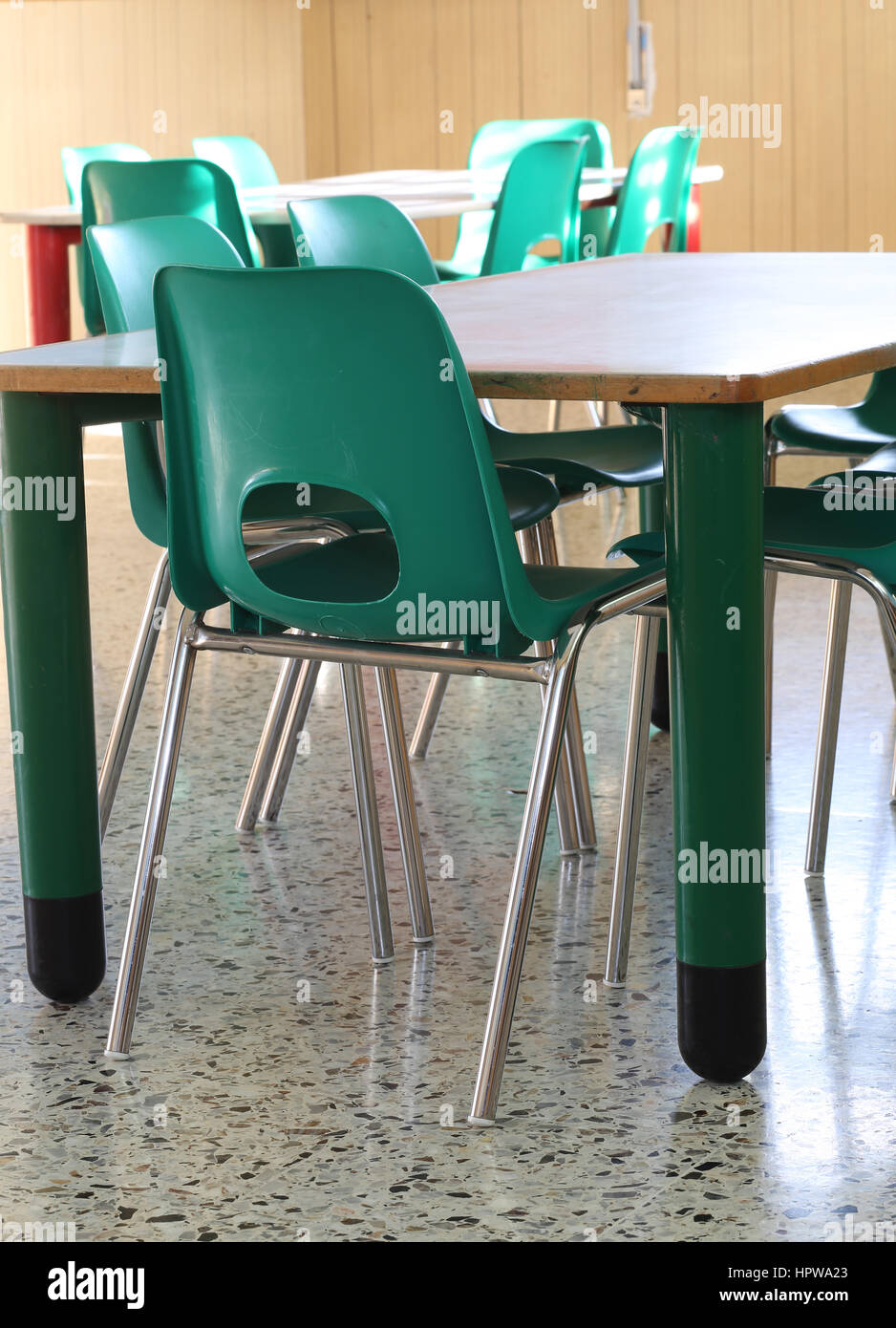 Inside the classroom of a school with green chairs and small tables ...