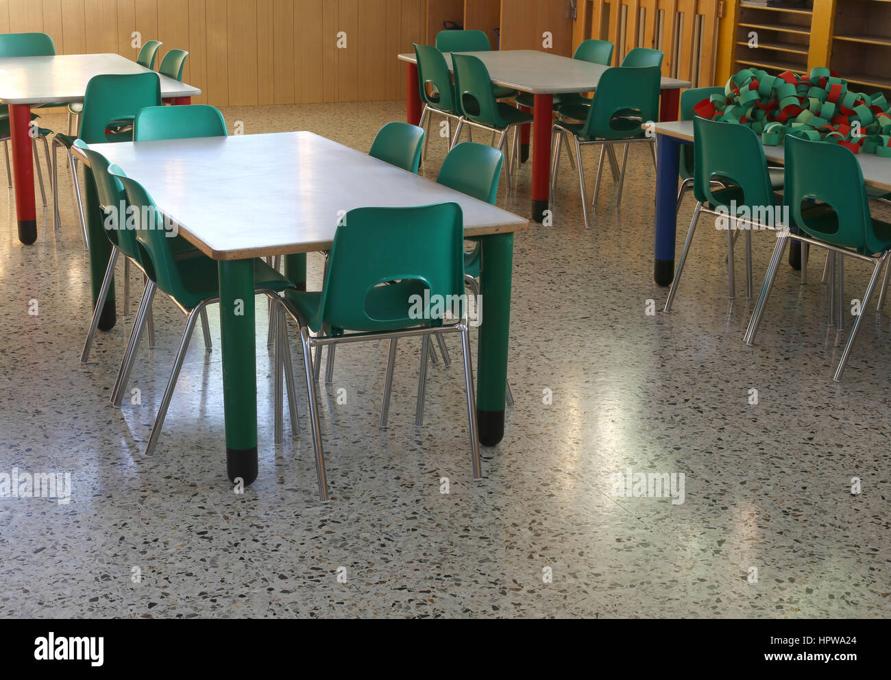 Inside the classroom of a school with green chairs and small tables to ...