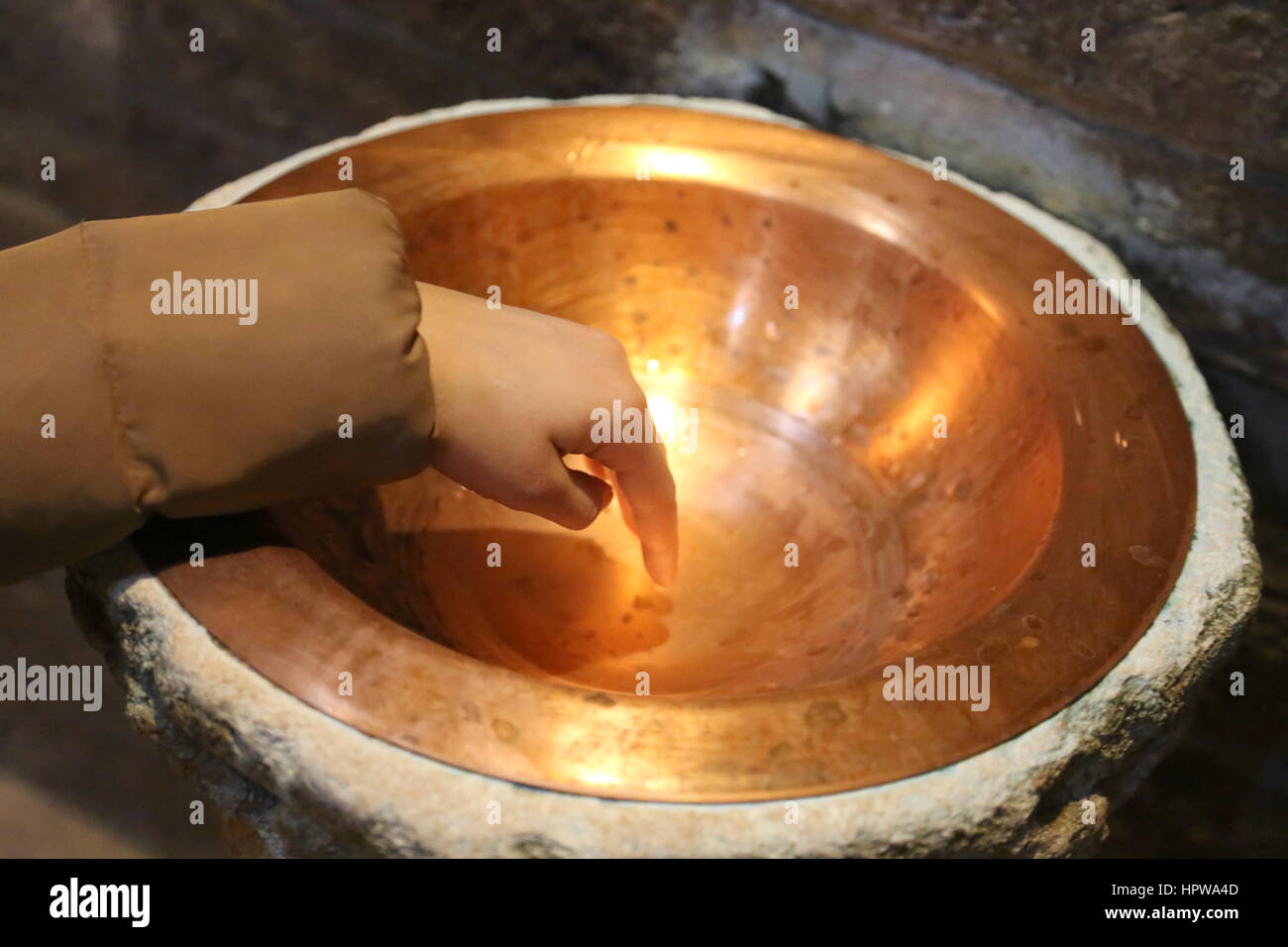 child's hand touching the holy water font on the stoup of the ancient ...