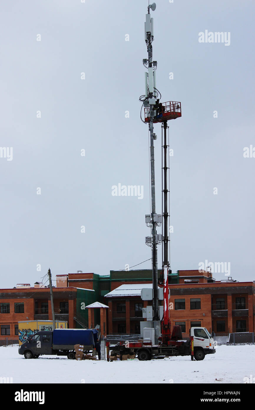 Two workers assemble equipment for telecommunications on the tower with ...