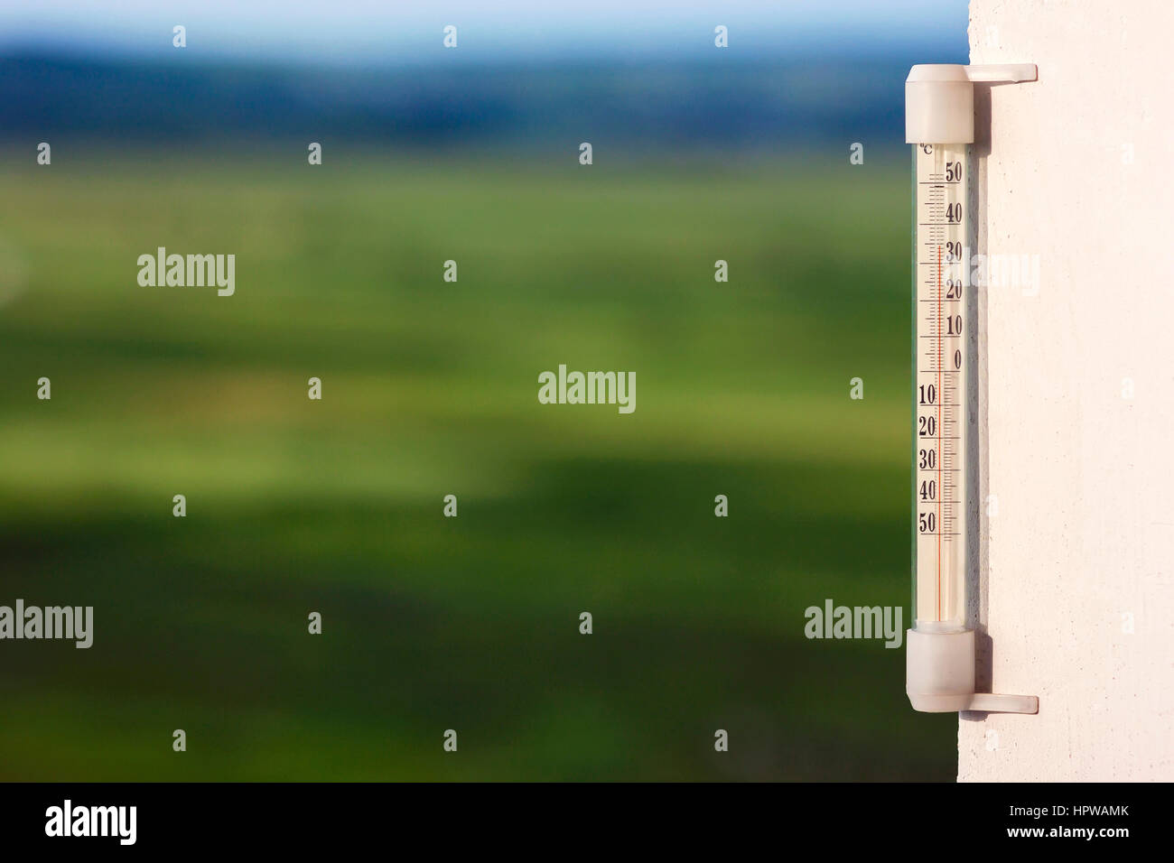 Thermometer celsius showing warm temperature on blurred green ...