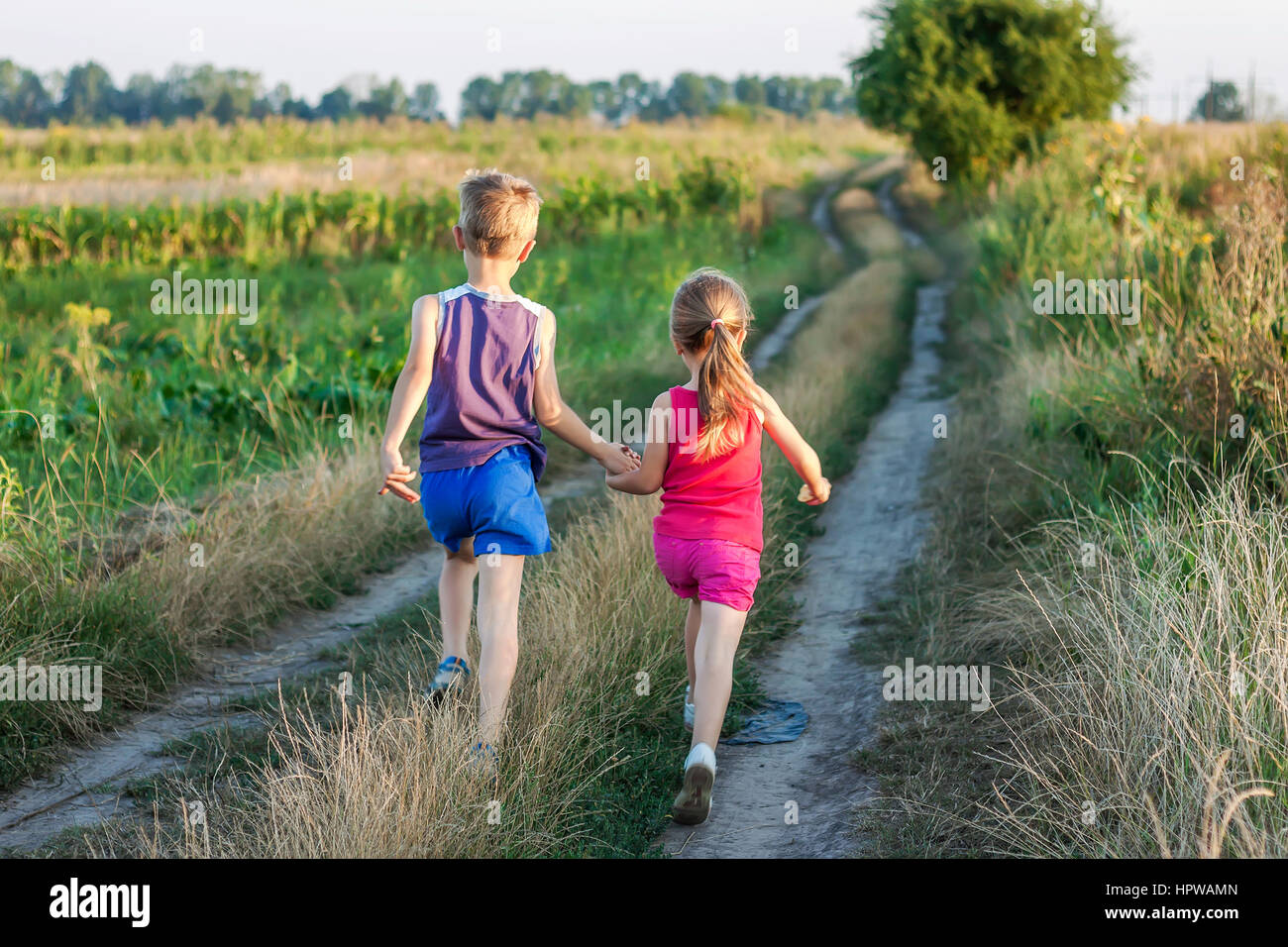 Little boy and girl running on a field road Stock Photo - Alamy