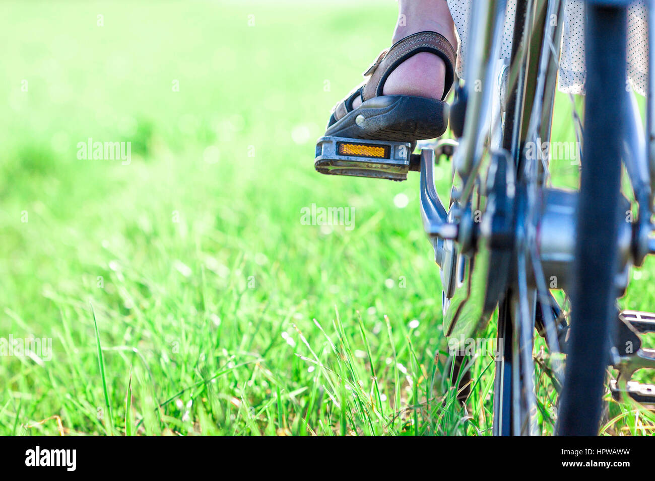 Womans foot on bicycle pedal on green grass closeup Stock Photo - Alamy
