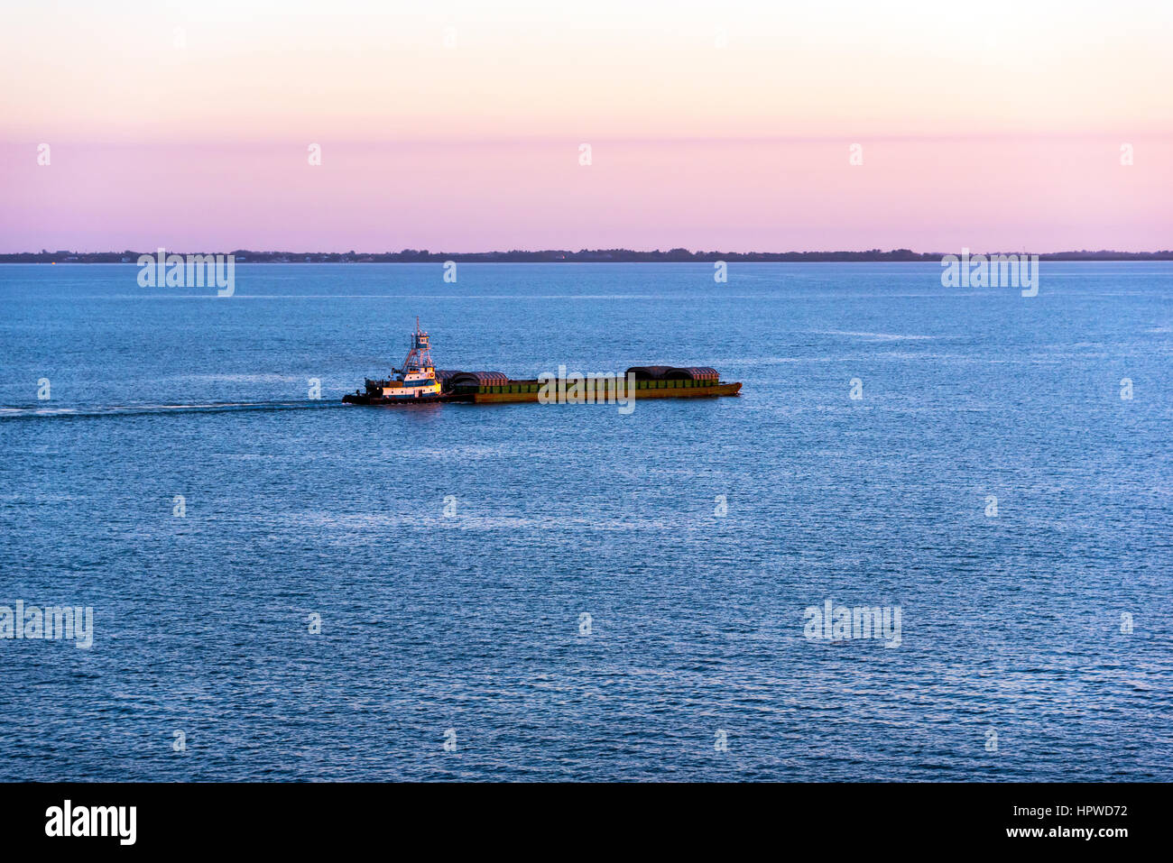 Tugboat pushing a barge across tampa bay at sunset Stock Photo - Alamy