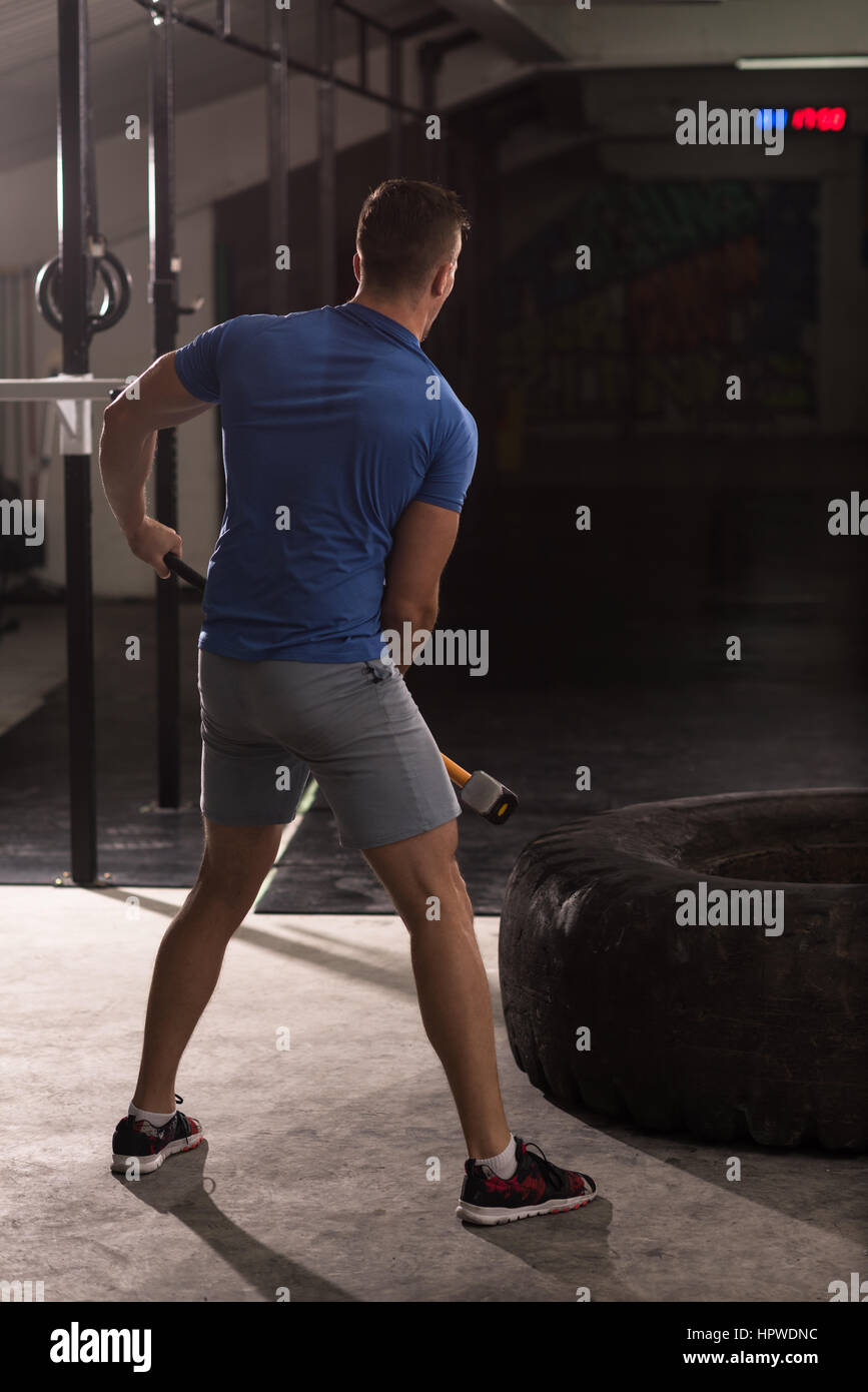 Sledgehammer Tire Hits young muscular man workout at gym with hammer ...