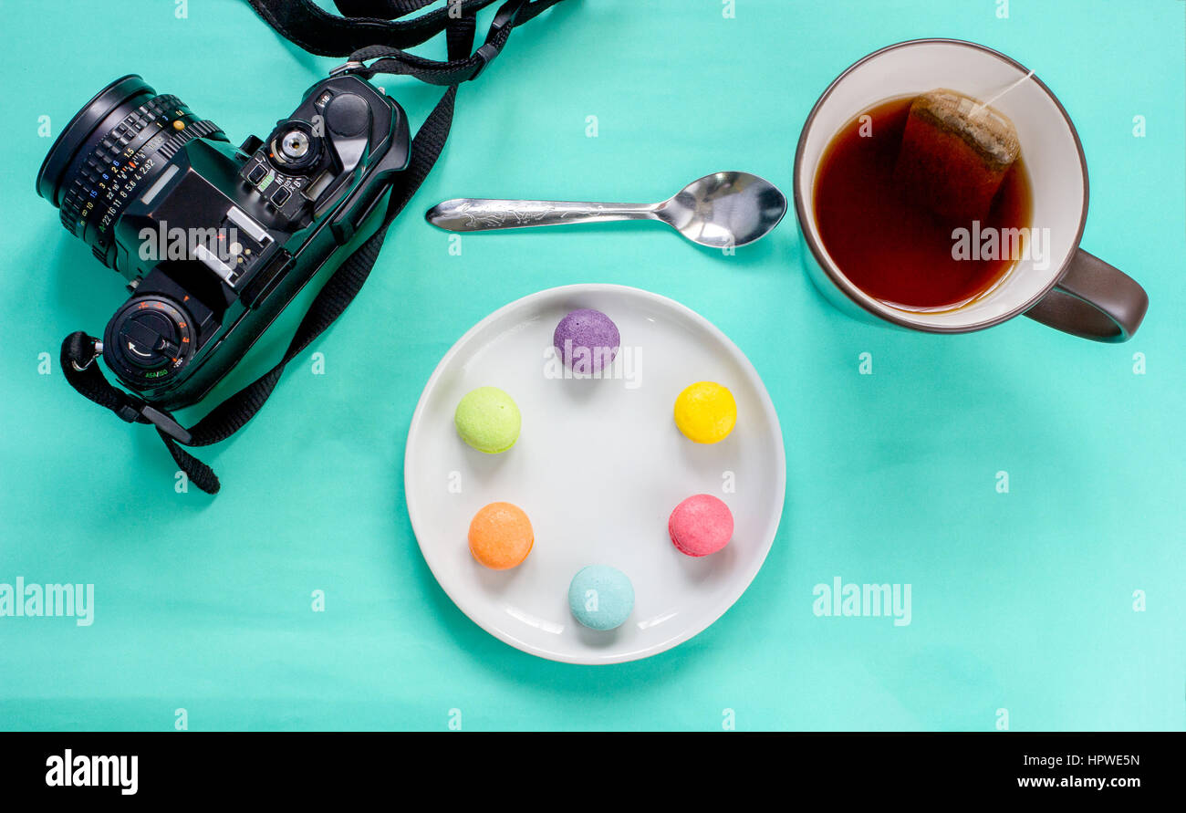 colorful french macaron,cup of tea and SLR camera on green background ...