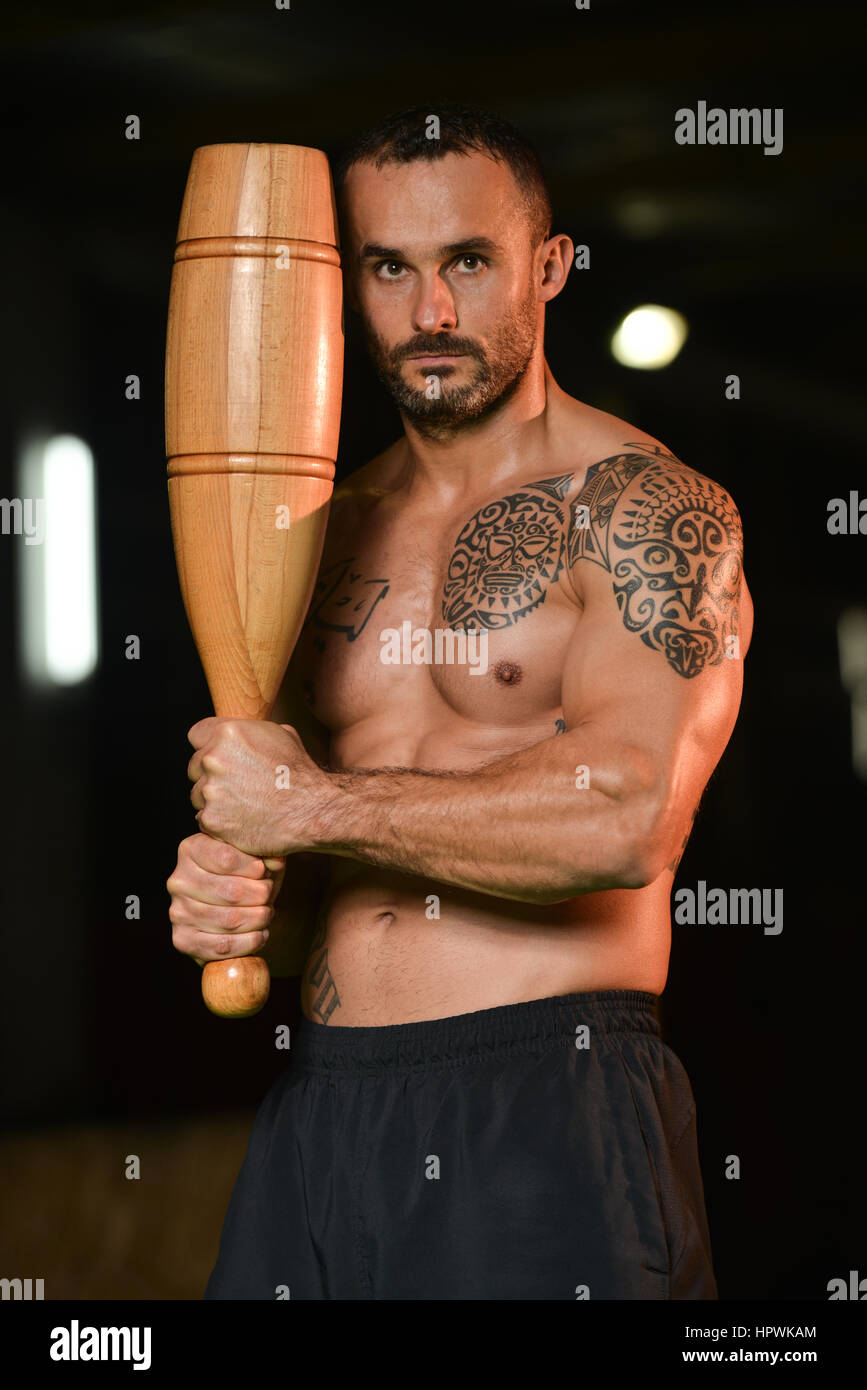 Young Man Exercising With Bowling Pin And Flexing Muscles - Muscular ...