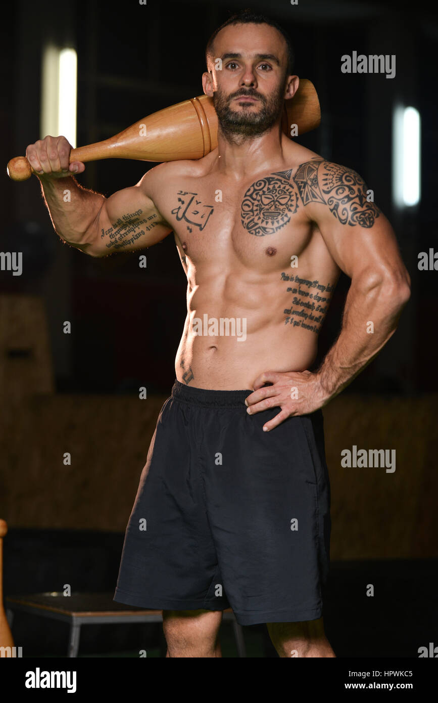 Young Man Exercising With Bowling Pin And Flexing Muscles - Muscular ...