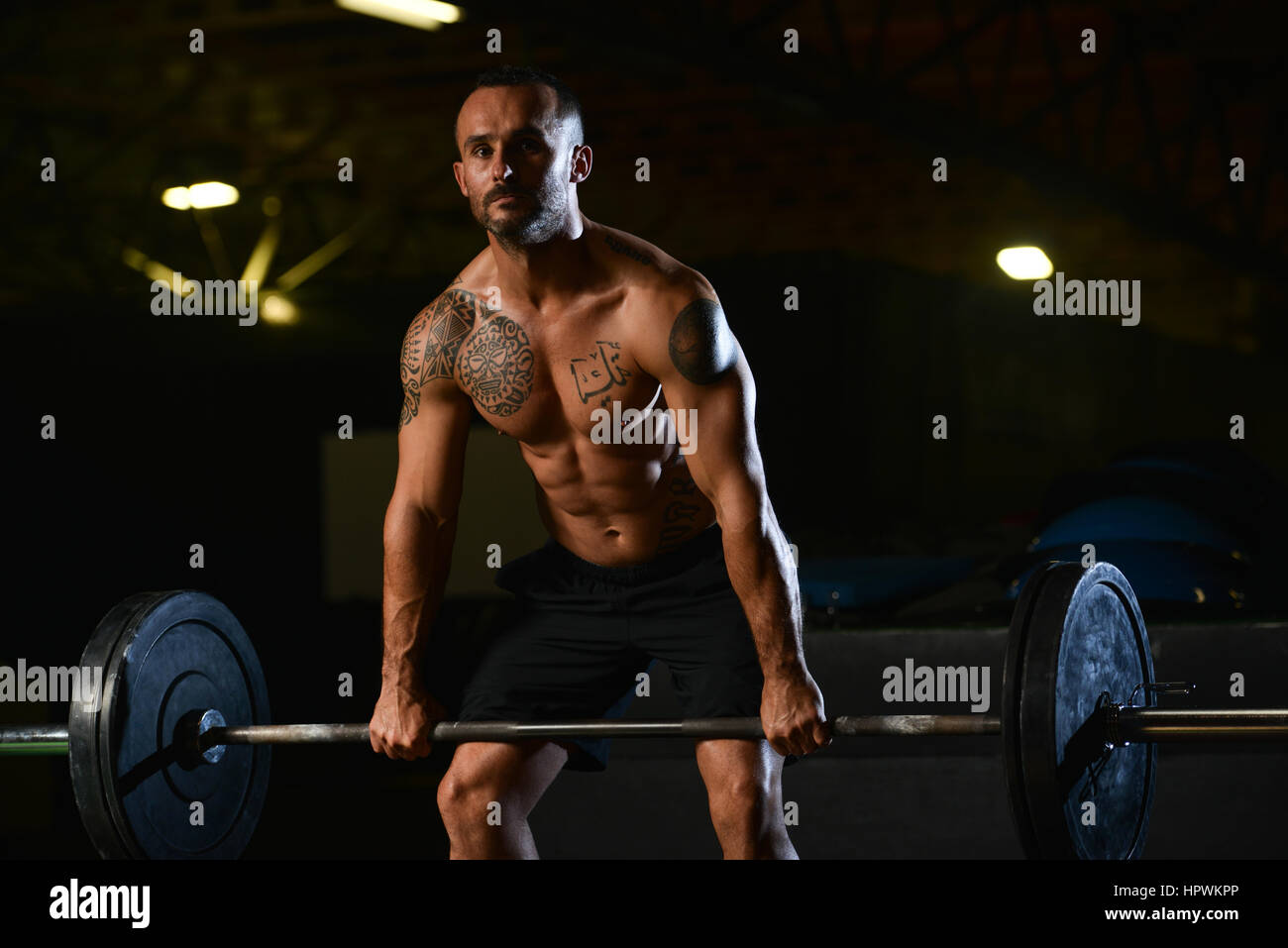 Muscular Man Doing Heavy Weight Exercise For Back With Barbell In Gym ...