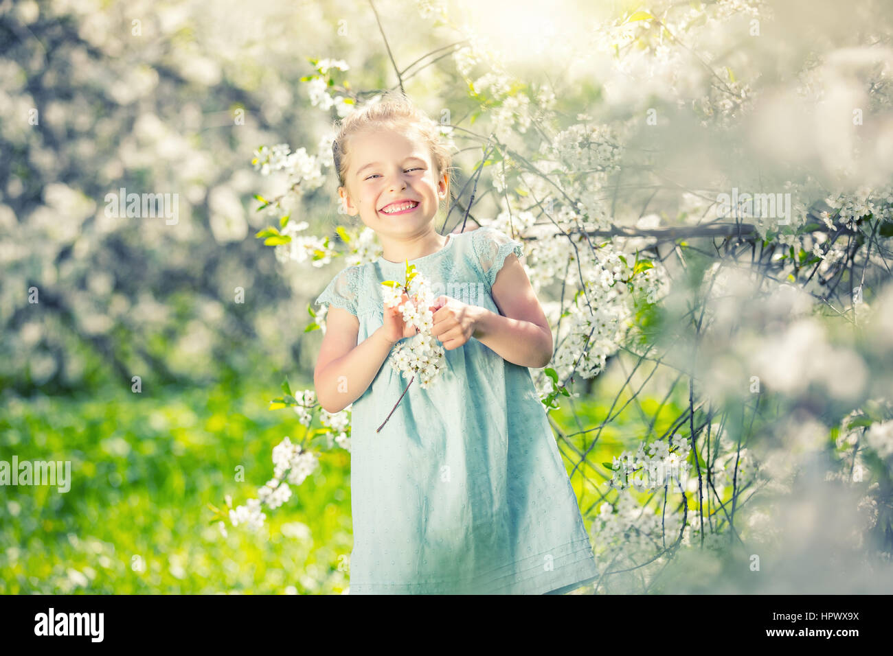 Happy little girl playing in spring cherry garden Stock Photo - Alamy
