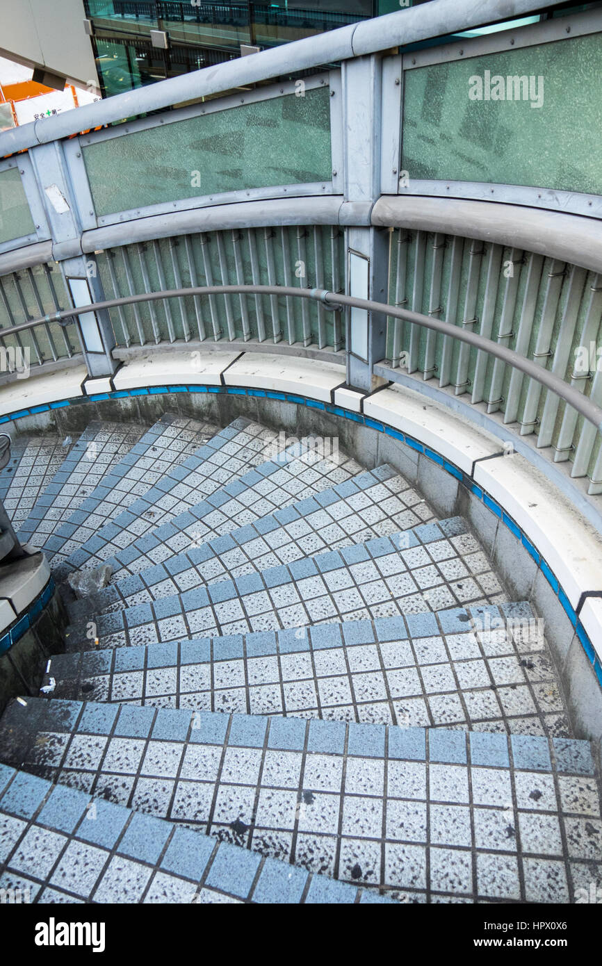 Pale blue tiled circular staircase of an overhead footbridge over Showa ...