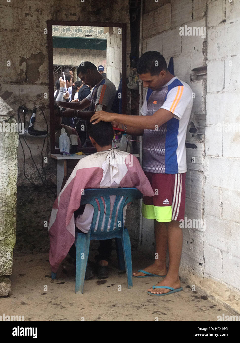 A young man getting a haircut by a street barber Stock Photo - Alamy