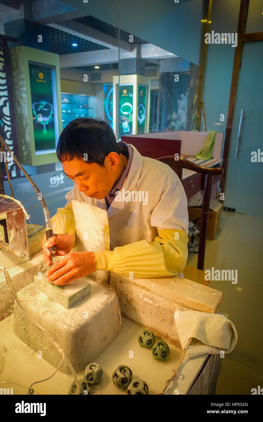 BEIJING, CHINA - 29 JANUARY, 2017: Jade craftsman sitting by desk using ...
