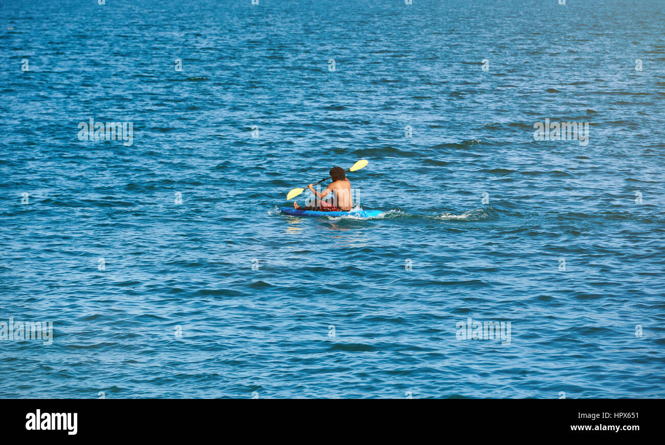 One man on blue kayak in deep lake water around. Kayak activity with ...