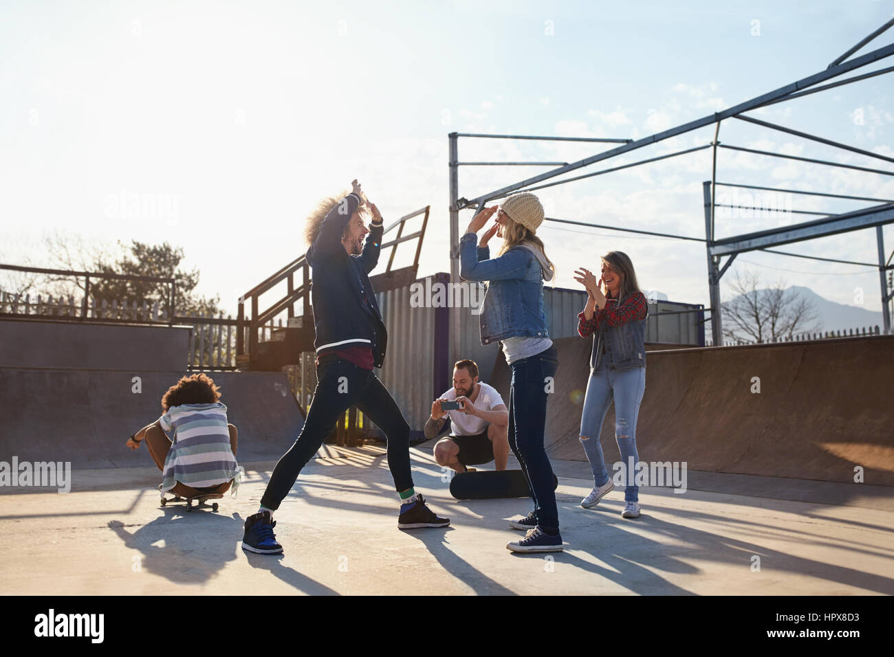 Friends high-fiving at sunny skate park Stock Photo - Alamy