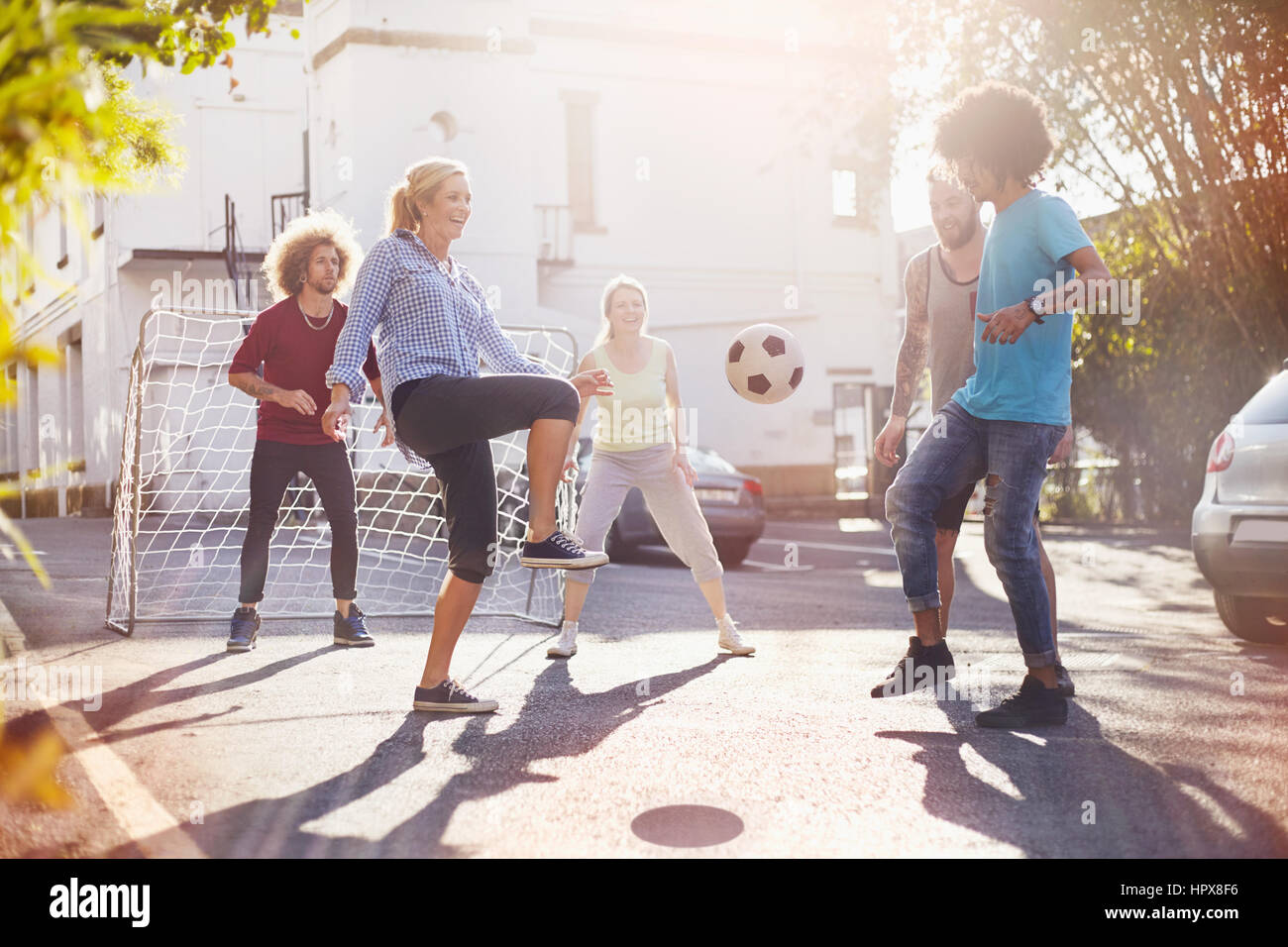 Friends playing soccer in sunny summer street Stock Photo - Alamy