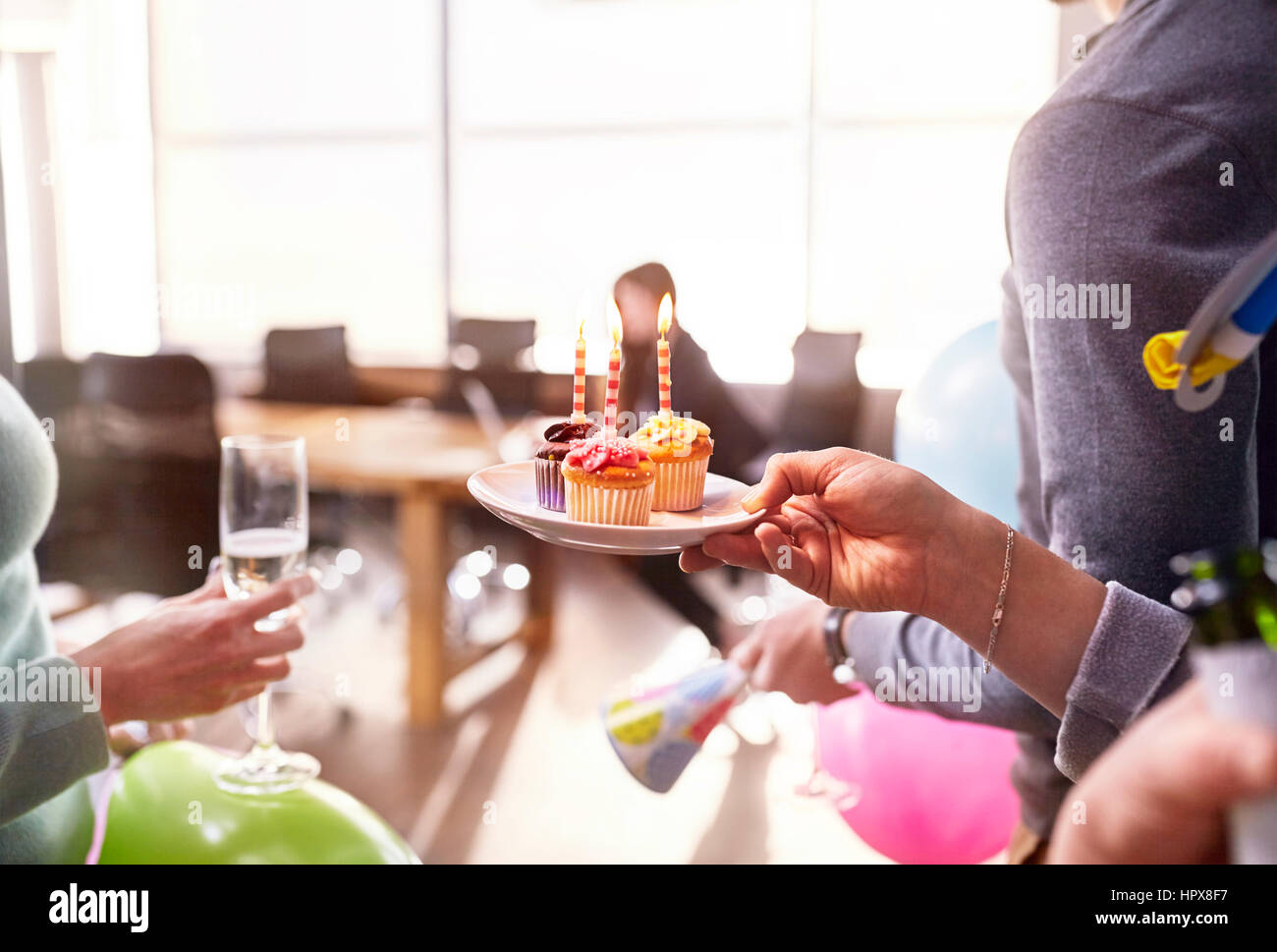 Businesswomen surprising coworker with birthday cupcake in conference ...