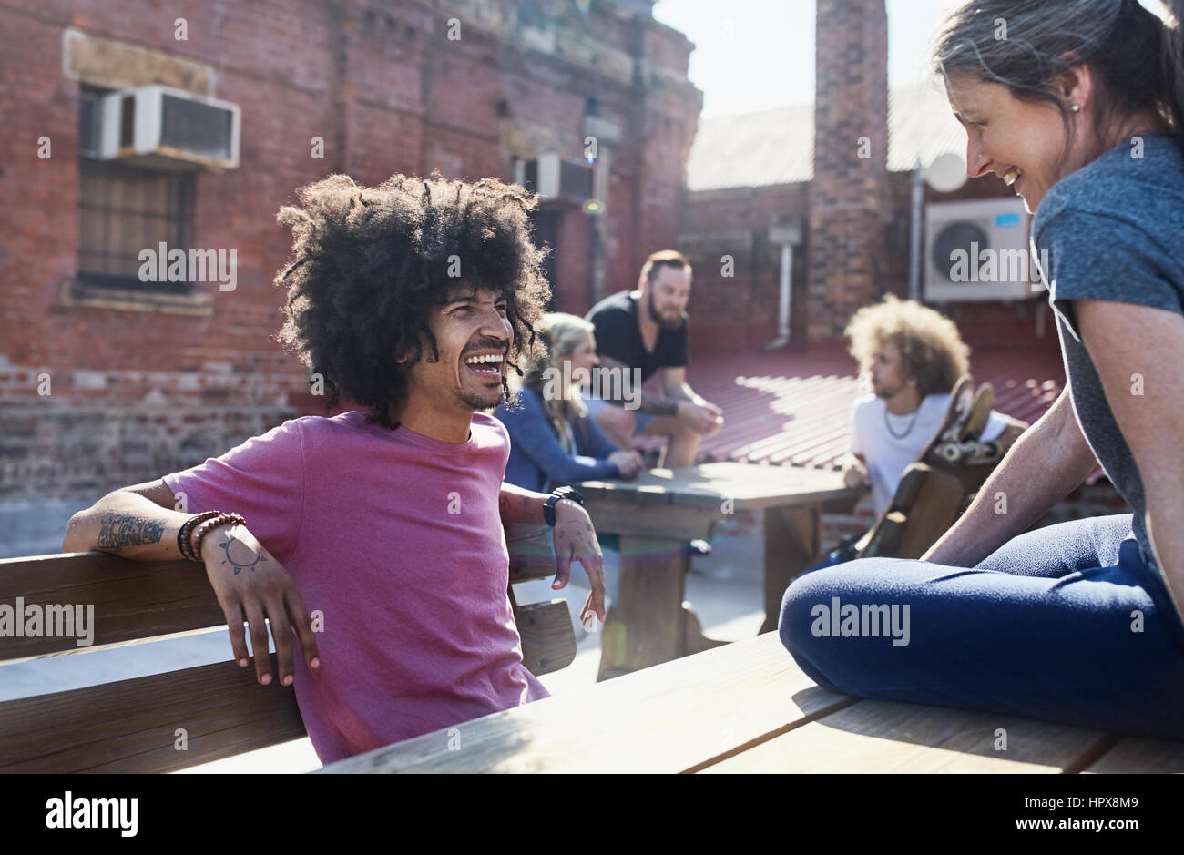 Smiling friends hanging out talking on sunny urban rooftop Stock Photo ...