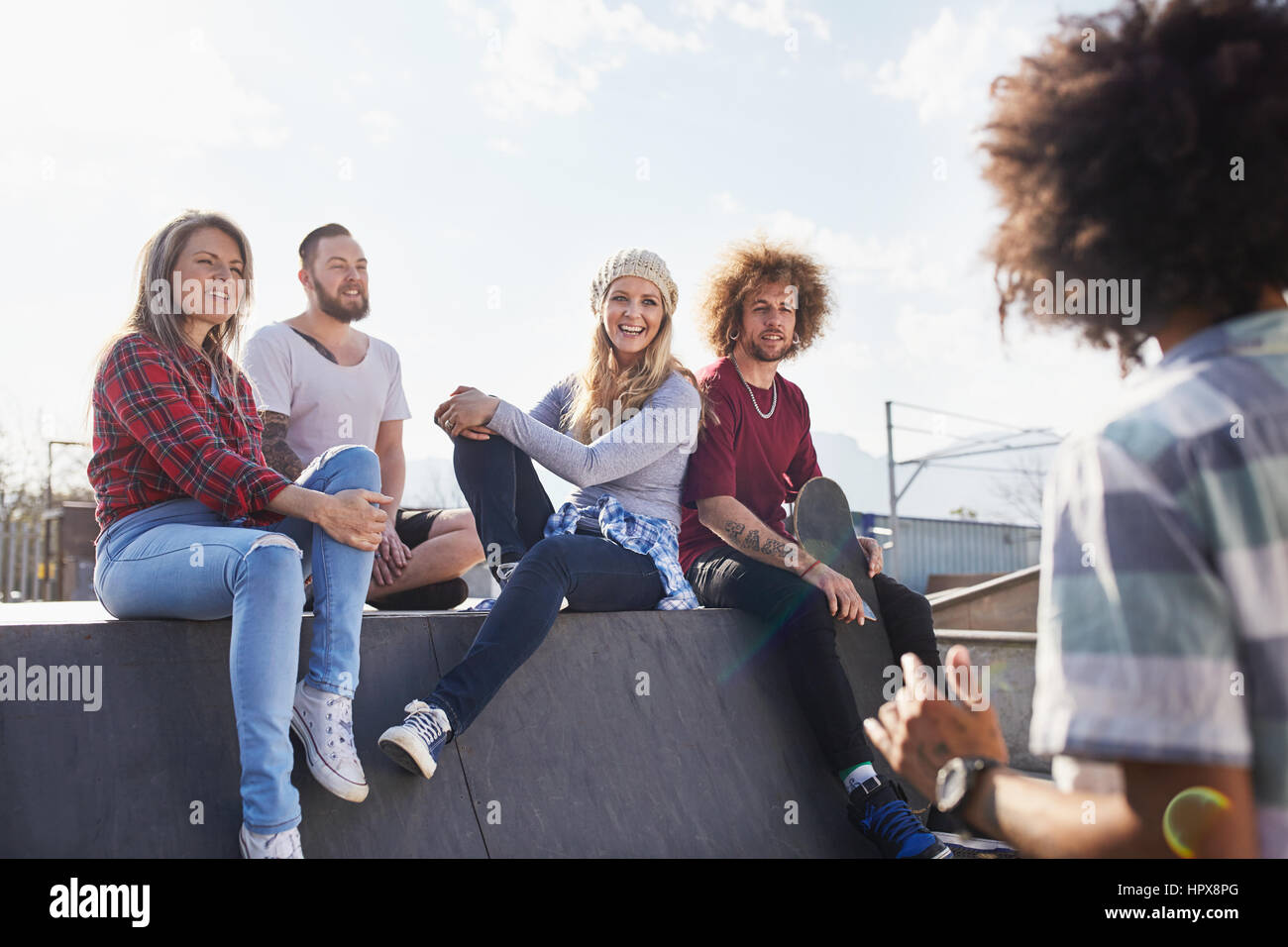 Friends hanging out and talking at sunny skate park Stock Photo - Alamy