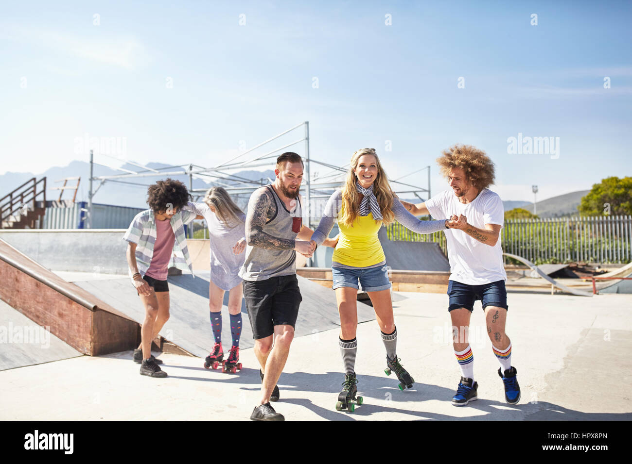 Friends roller skating at sunny skate park Stock Photo - Alamy