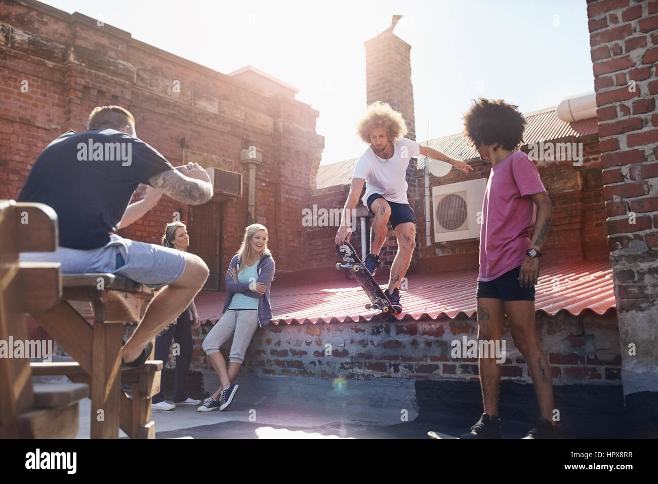 Man with camera phone photographing friend doing skateboard stunt on ...