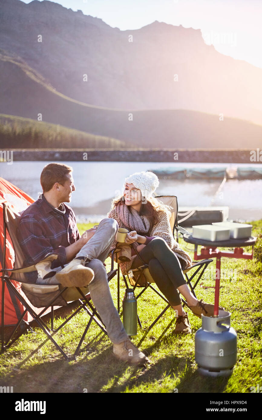 Young couple camping, drinking coffee at sunny lakeside campsite Stock ...
