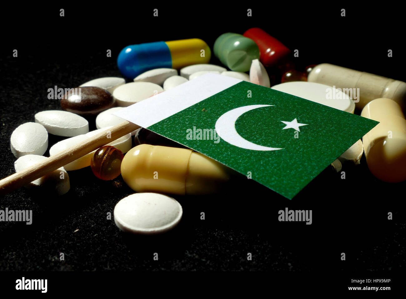 Pakistani flag with lot of medical pills isolated on black background ...