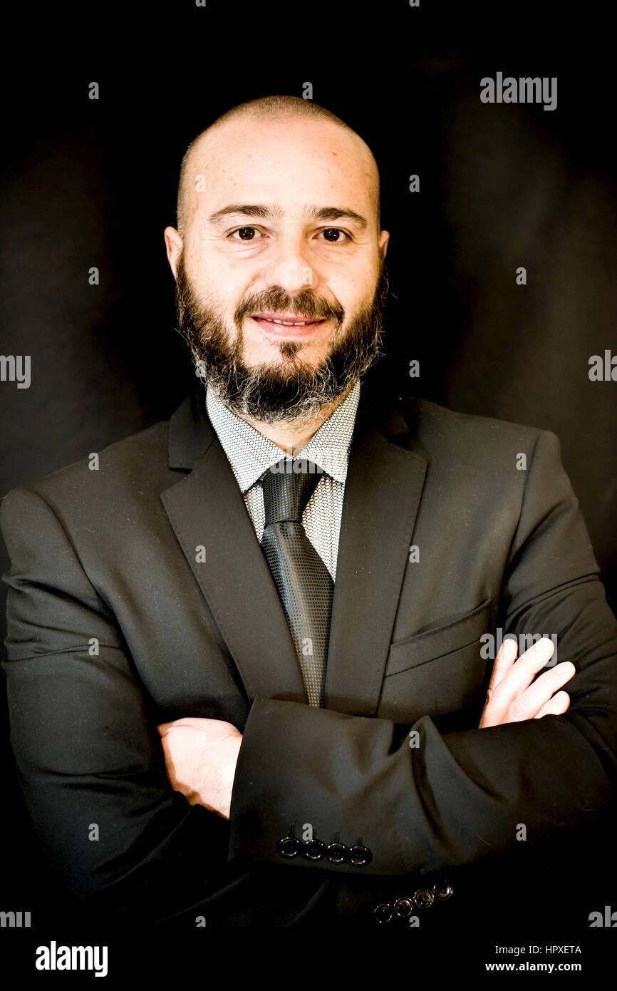 Handsome, bald man with beard, in suit and tie, on black background ...
