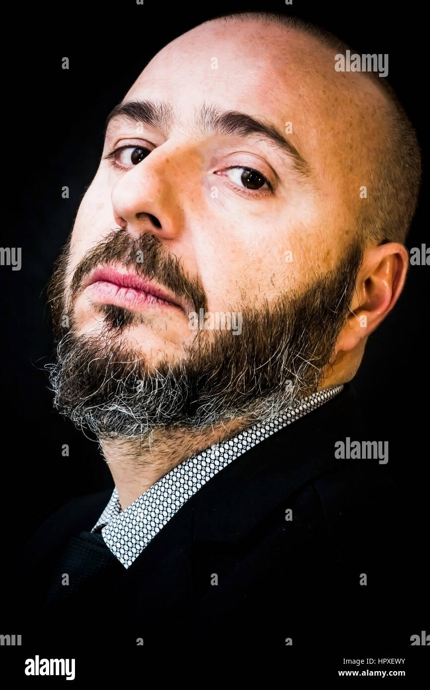 Handsome, bald man with beard, with suit and tie, on black background ...
