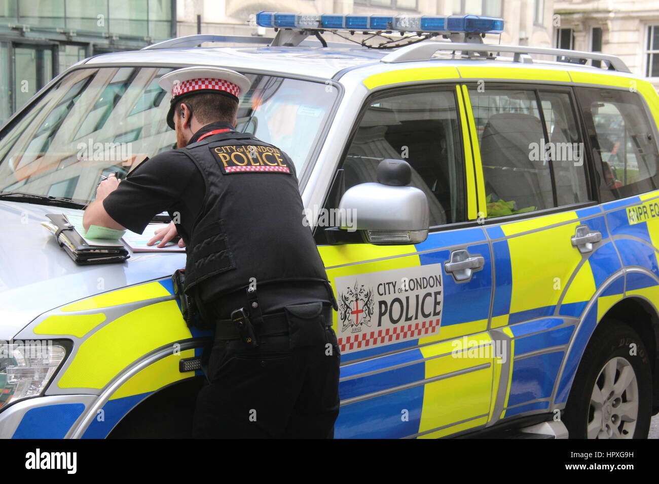 A CITY OF LONDON POLICE OFFICER LEANING ON THE BONNET OF A POLICE CAR ...
