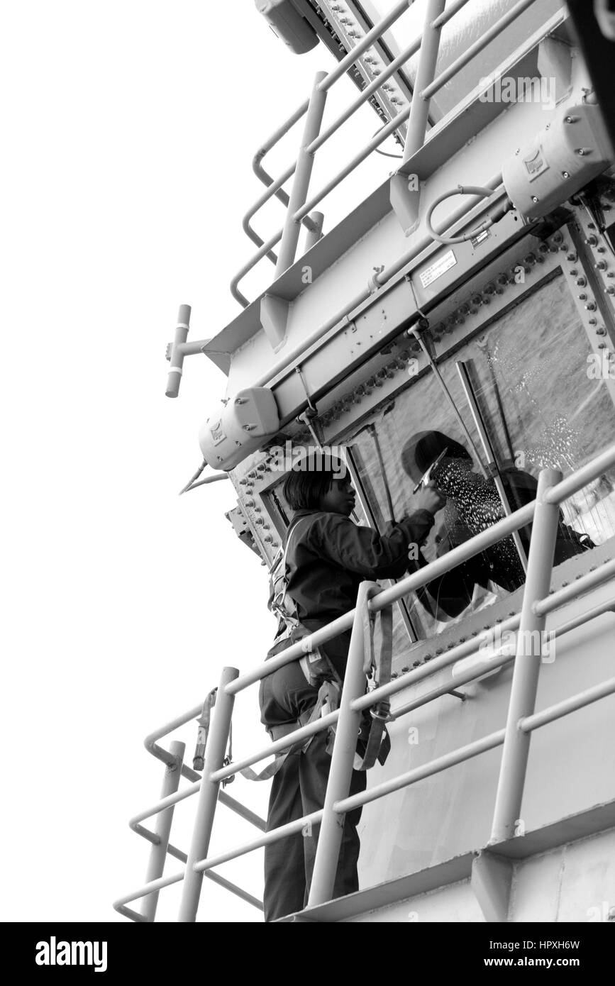 A sailor cleans the windows on the bridge abroad the aircraft carrier ...