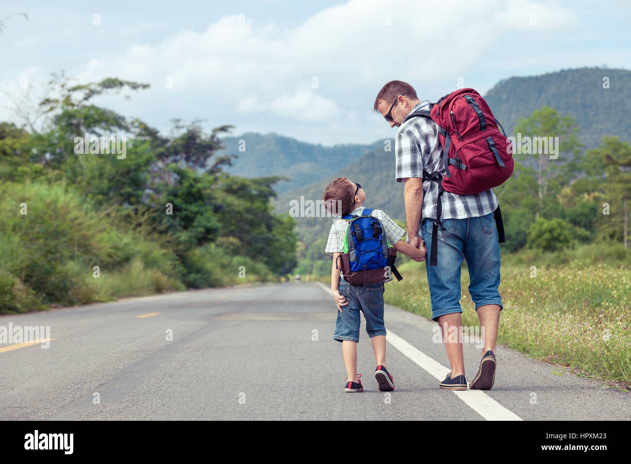 Father and son walking on the road at the day time. Concept of friendly ...