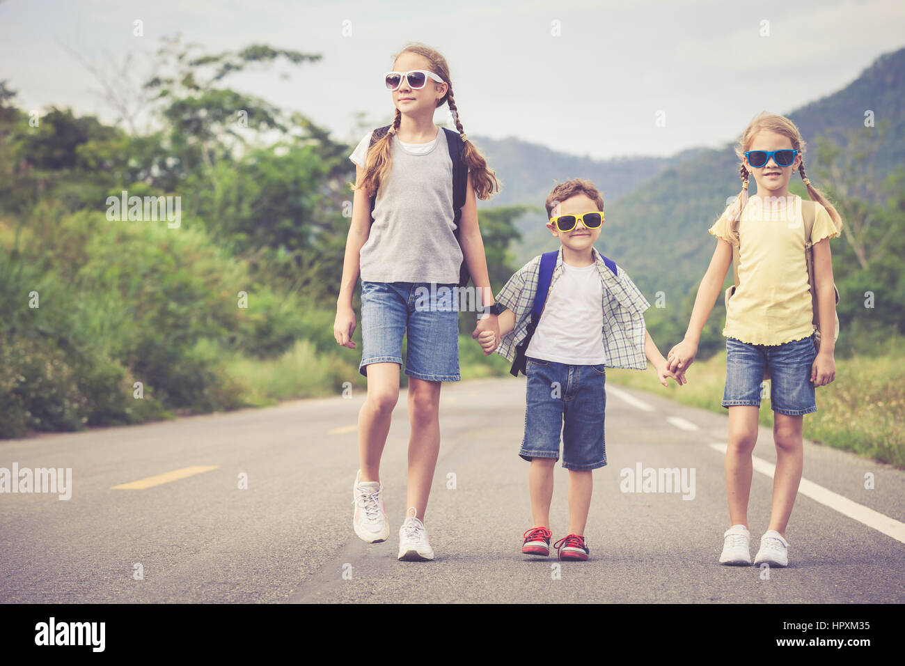 Happy children walking on the road at the day time. Concept of friendly ...